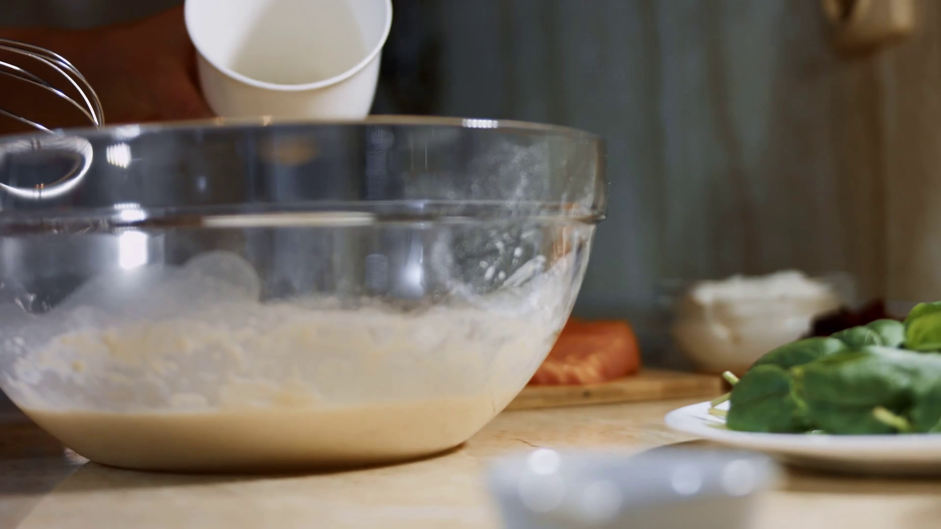 Mixing ingredients with steel whisk in a glass bowl, adding milk ...