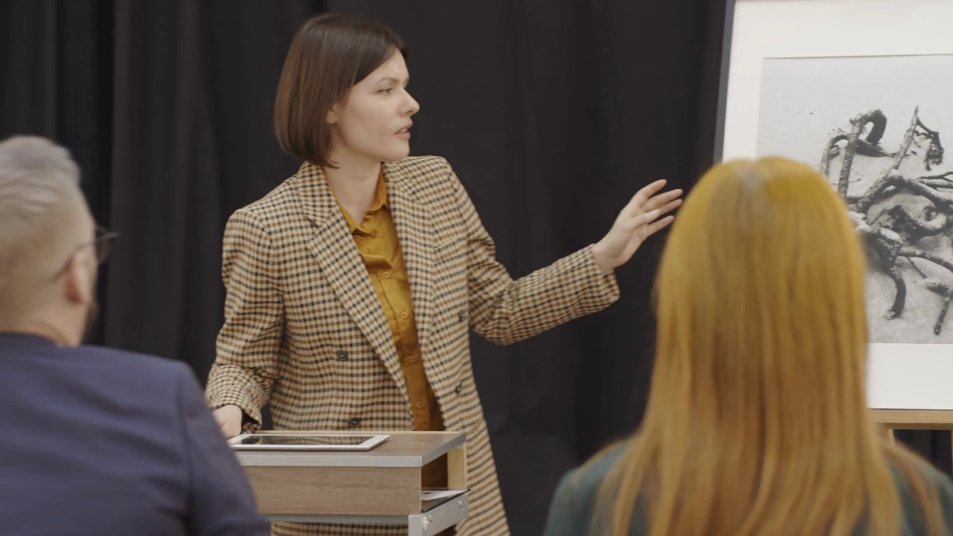 female auctioneer standing at lectern and presenting photography to ...