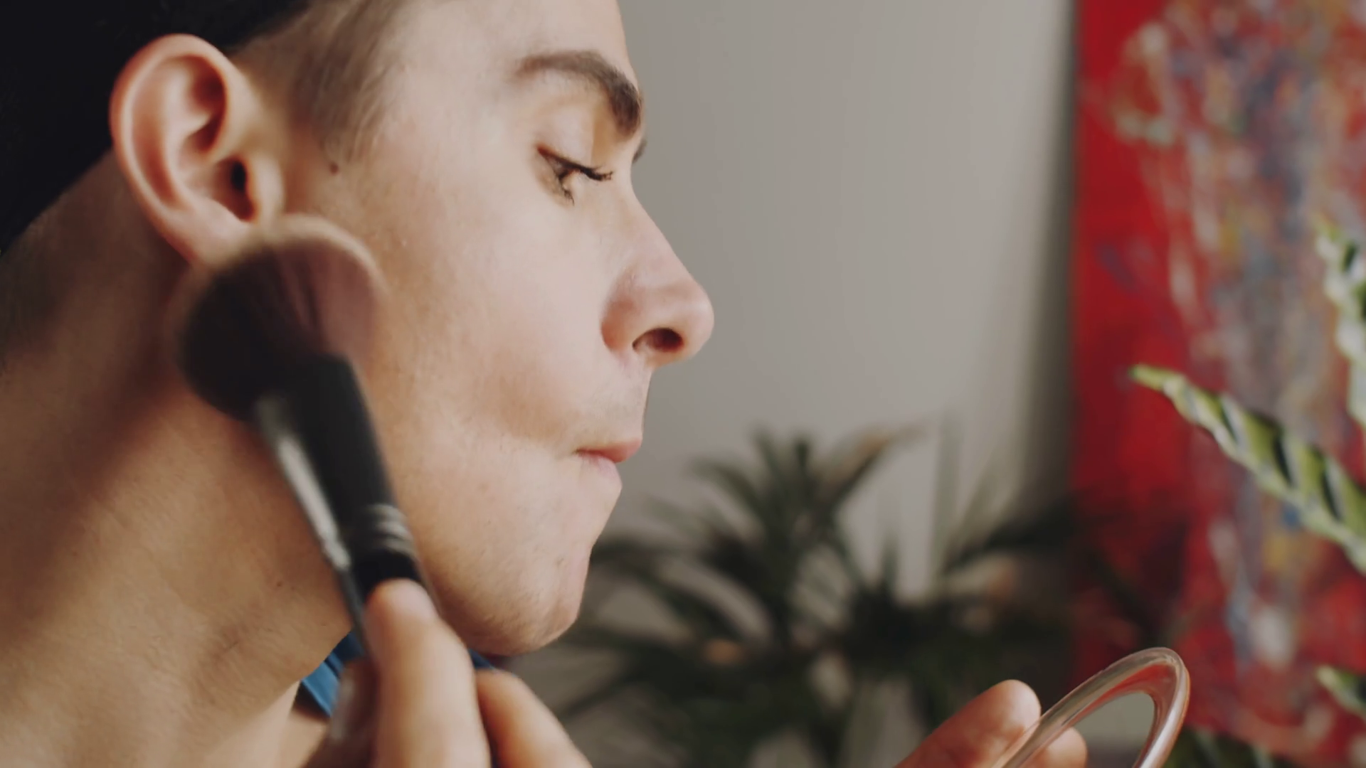 Close up shot of young transgender man in hairnet applying bronze ...