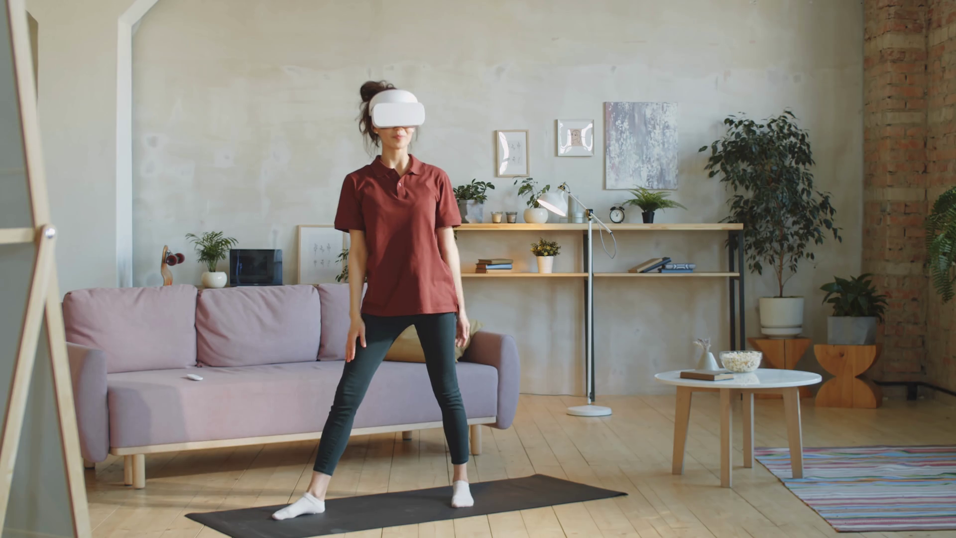Young woman in VR headset practicing forward fold on mat at home while ...