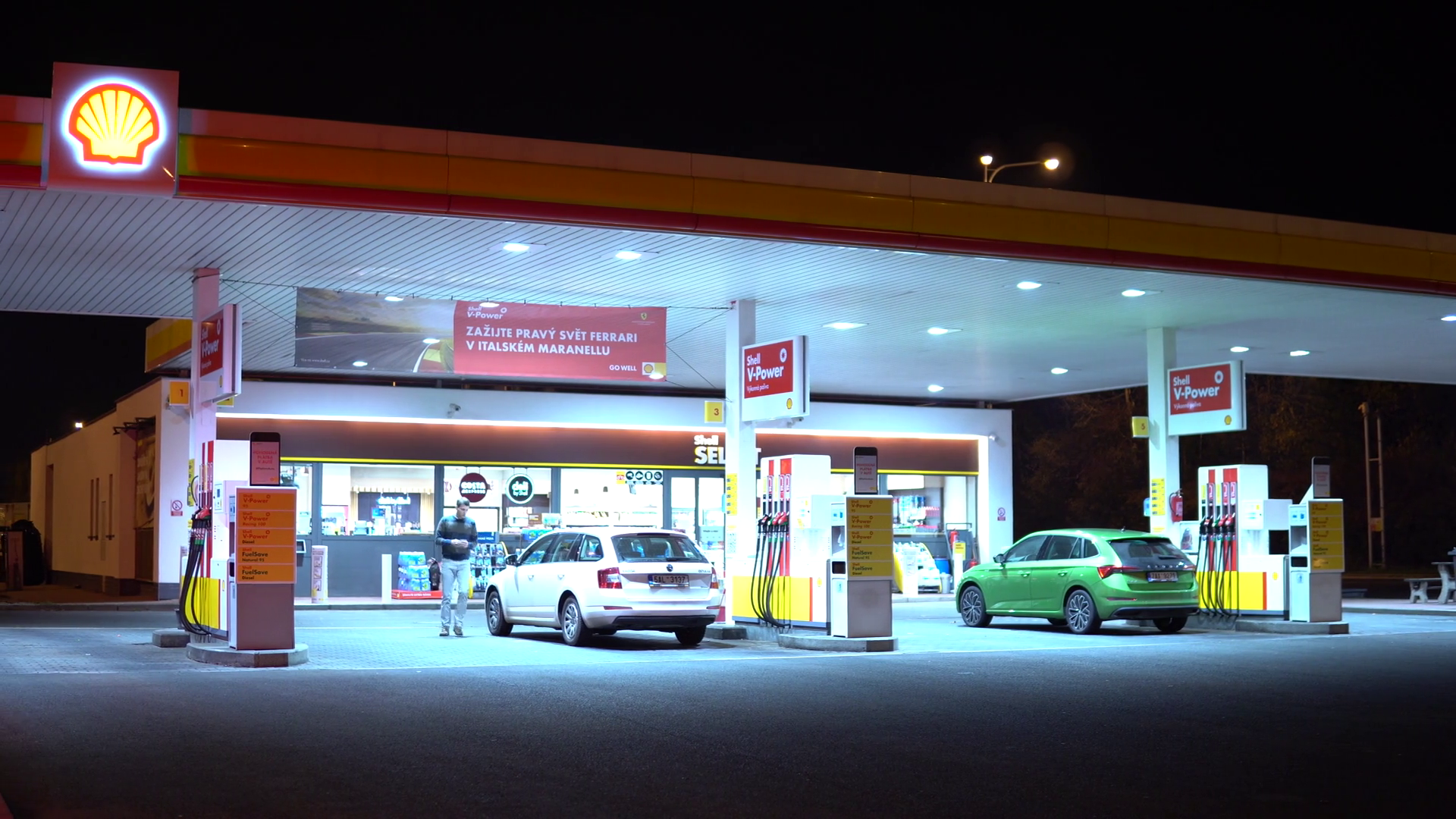 A gas station on a dark night, a car drives into the gas station, a man ...