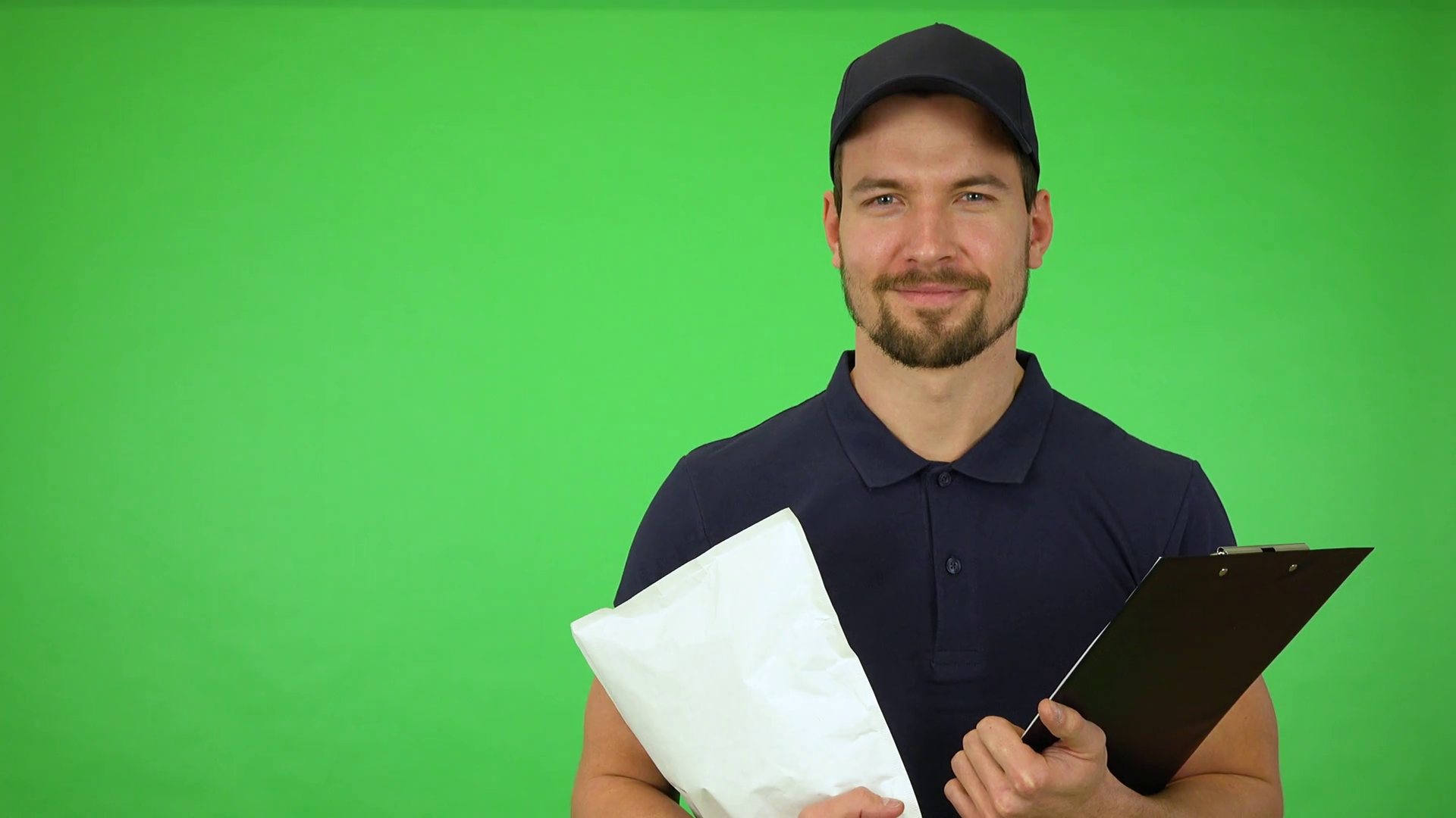 A young handsome mailman smiles at the camera - green screen studio ...