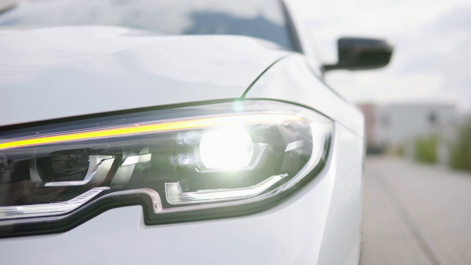 Shining headlight and front blinker of a white modern car in a suburban ...