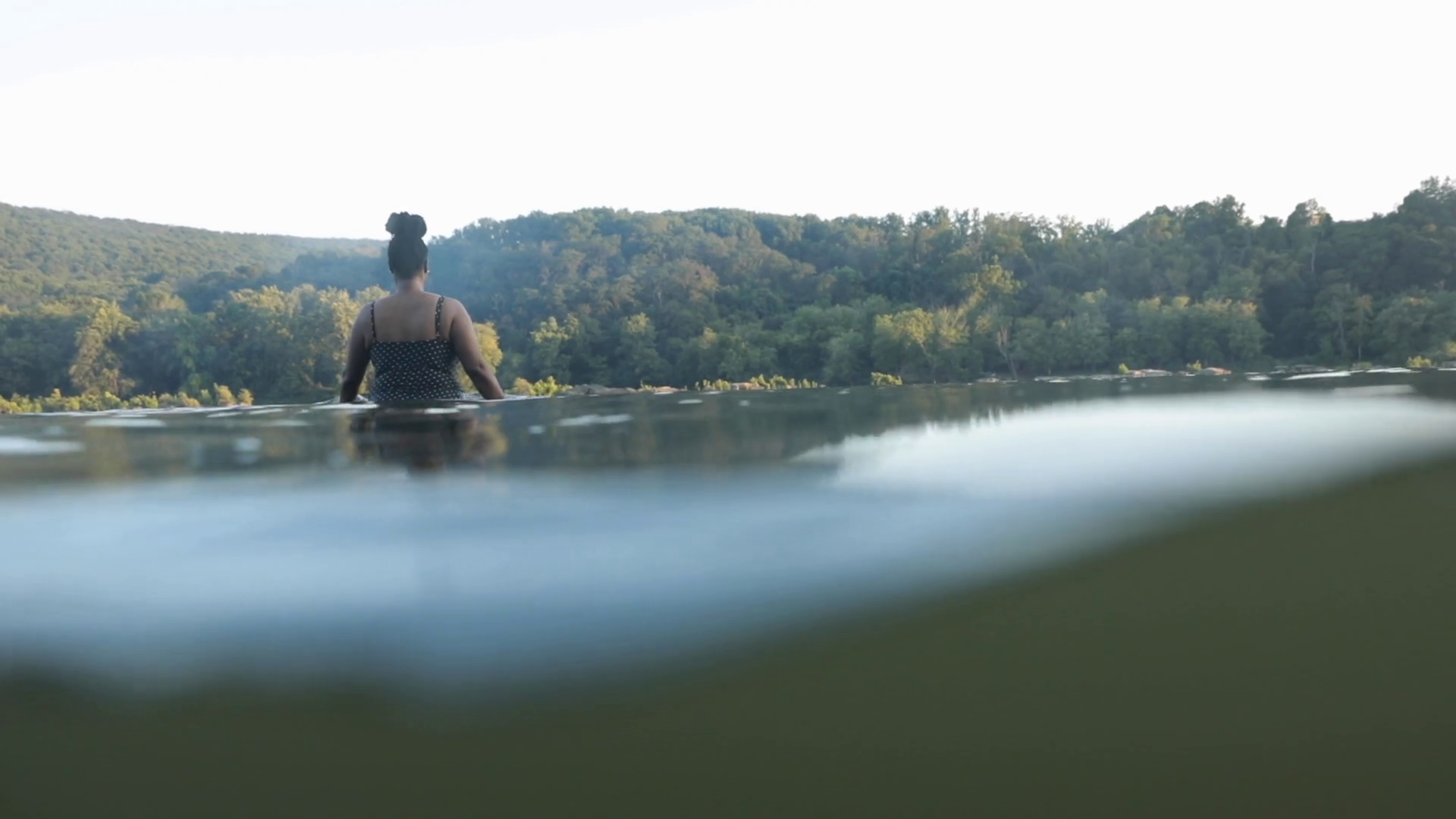 Static rear view of a young black woman wading into a rural river Stock ...