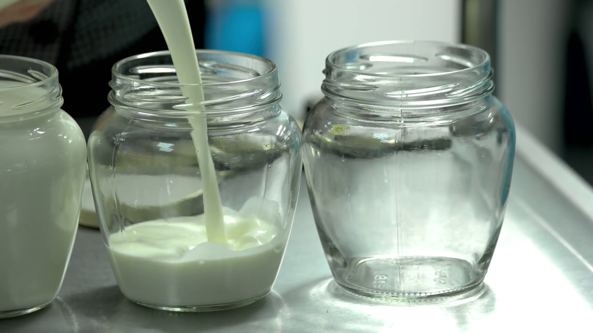 Close up glass jars filling with fresh milk. Milk pouring into glass ...