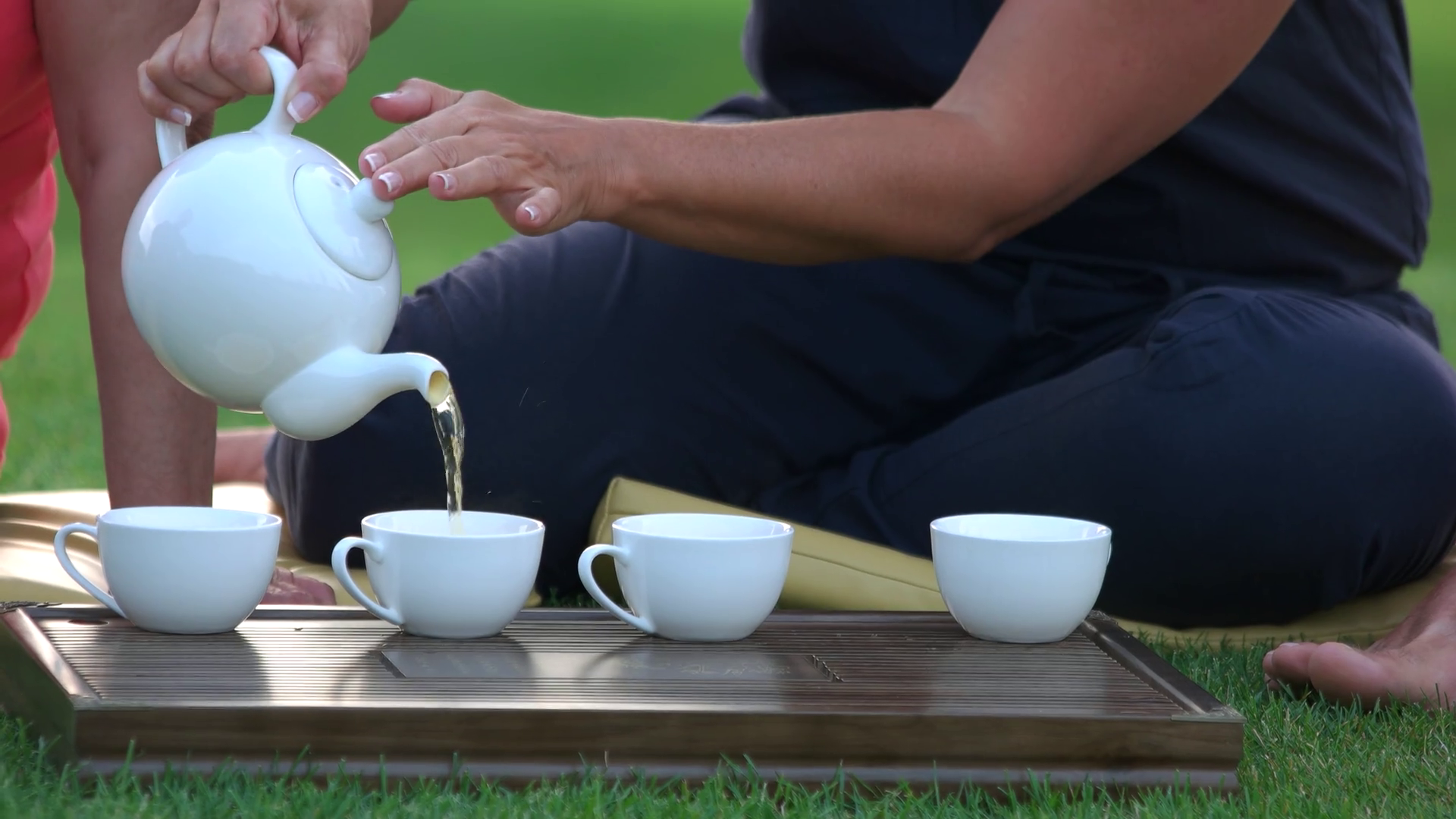 Close up woman pouring tea in cups outdoors. Traditional white tea set ...