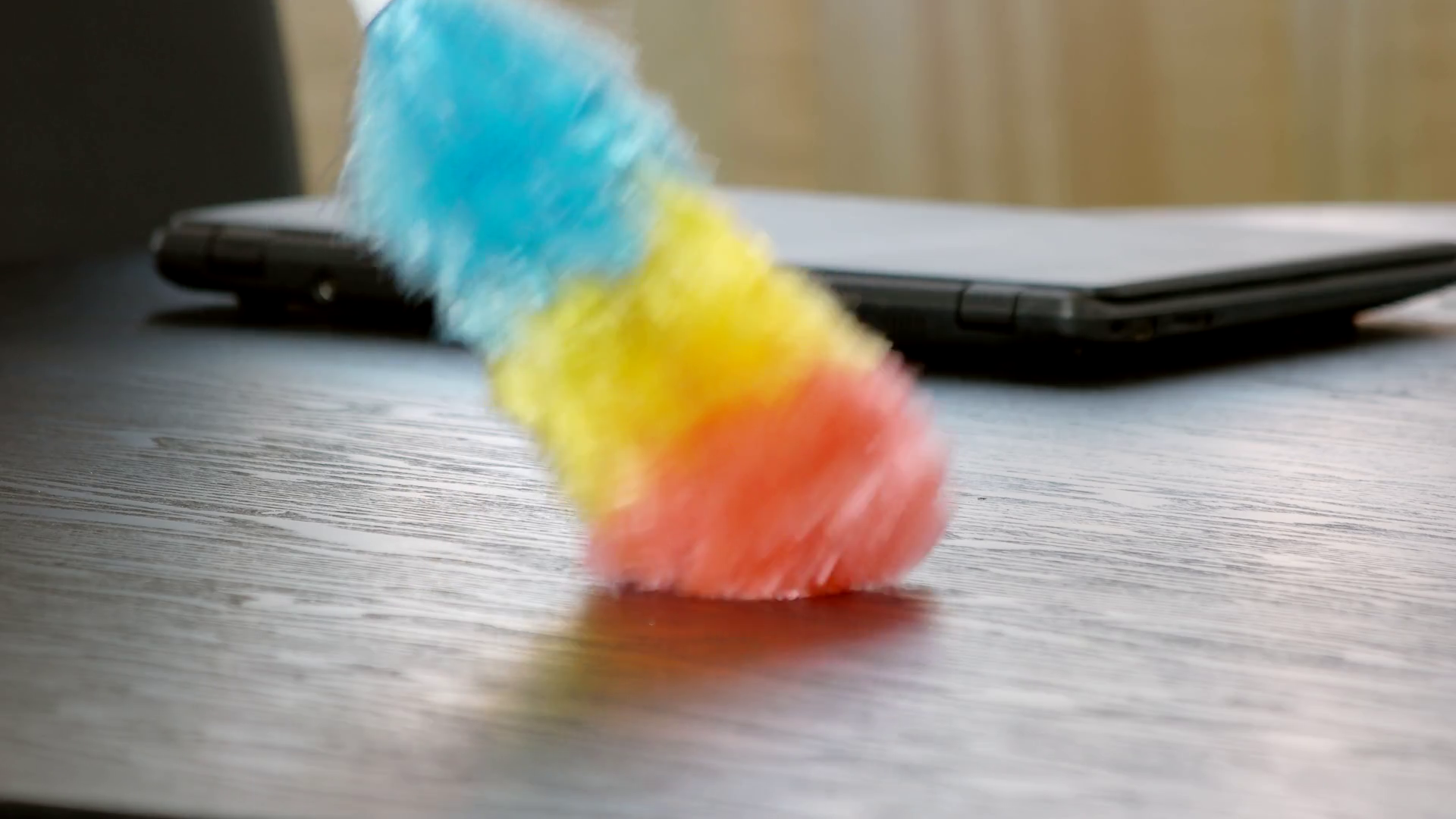 Colorful duster close up. Dust brush wiping wooden table. Office ...
