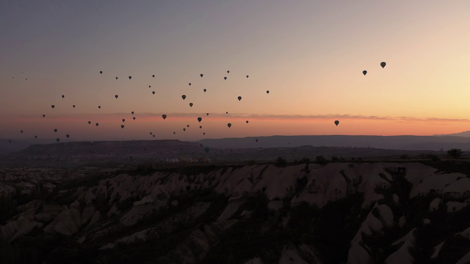 Colorful hot air balloons flying over rocky landscape at sunset sky ...