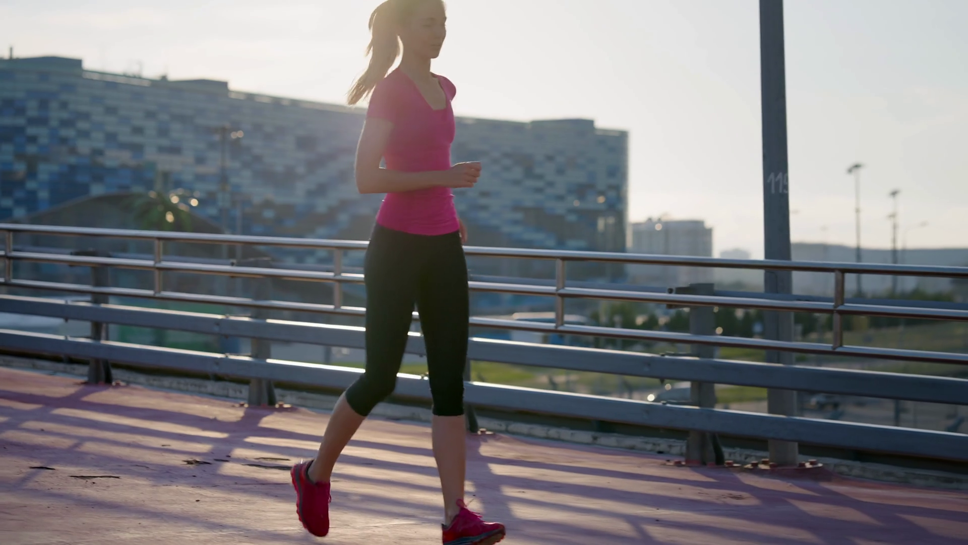 Slow motion shot of a slim and fit woman jogging on running track in ...