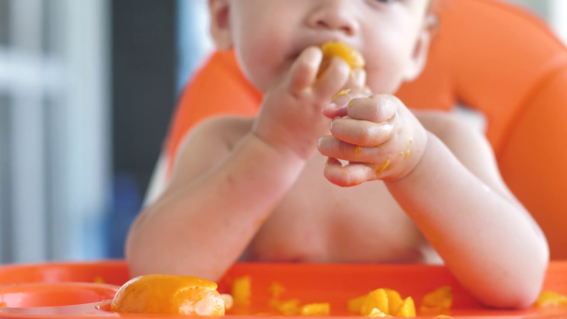 Close-up of a cute baby with pleasure eating fruit himself while ...