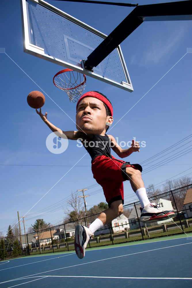 A basketball player with a large head driving to the hoop with some ...