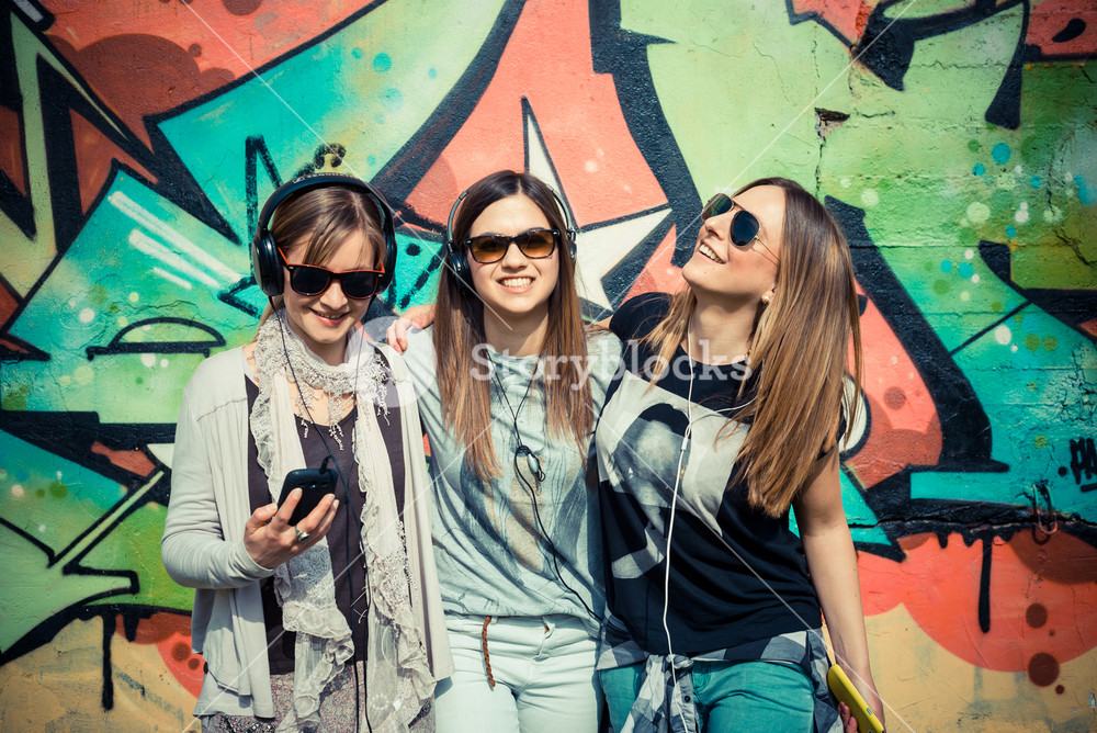 Three friends enjoying music in an urban setting Royalty-Free Stock ...